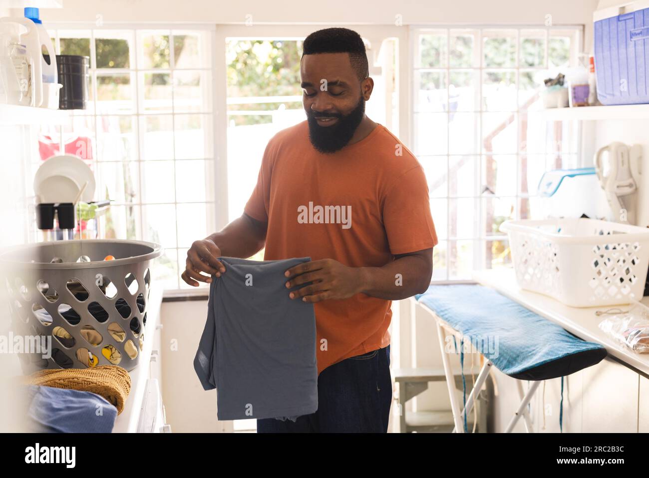 Happy african american man holding washing in kitchen with washing ...