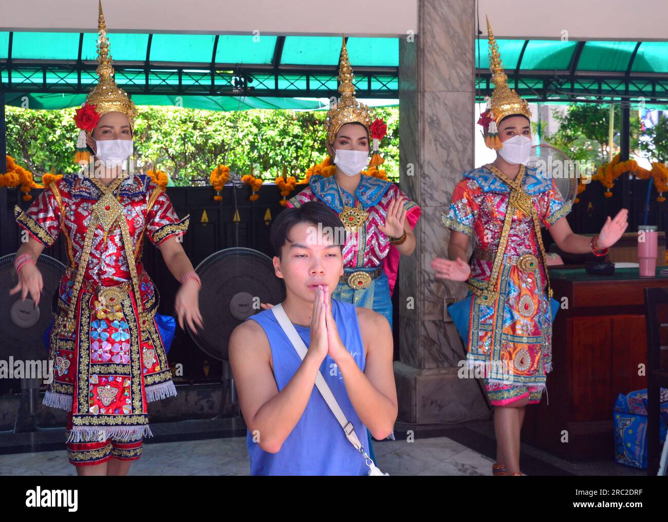 A young man prays in front of women dancers in traditional costumes at ...