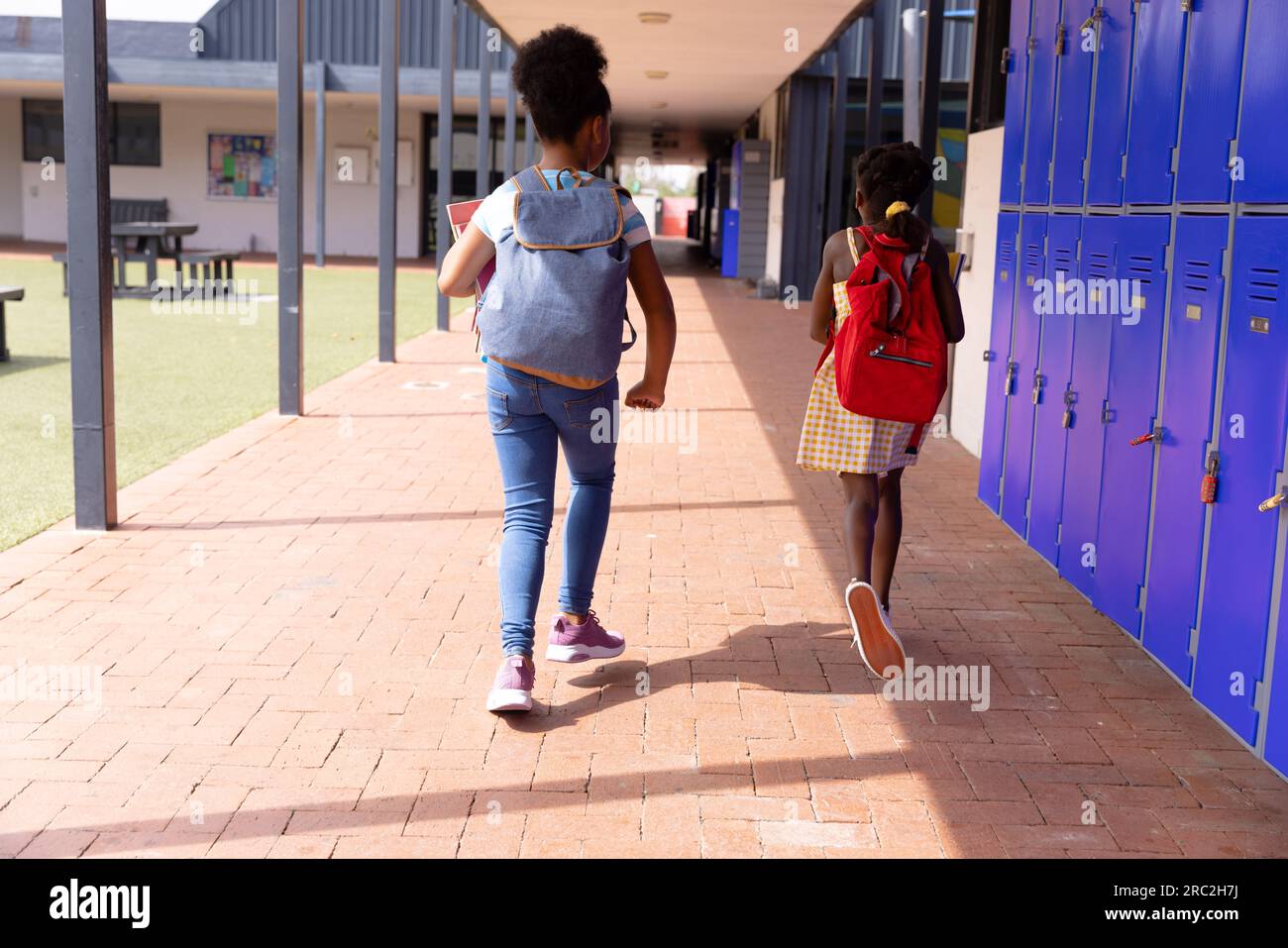Happy african american schoolchildren walking with school bags at ...