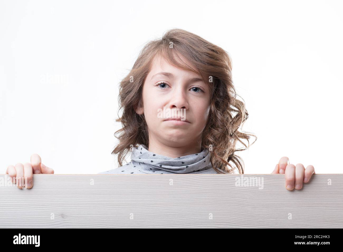 Girl holds wooden sign with room for copyspace, making a disgusted, sad ...