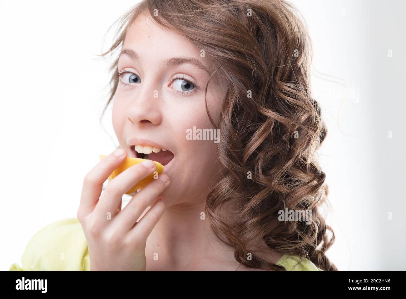 Enjoying the sour-sweet vitality of a fresh lemon, a girl embodies ...