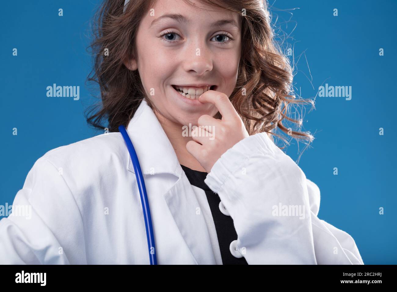 Girl in doctor's outfit touches teeth with a sly smile. She might be ...