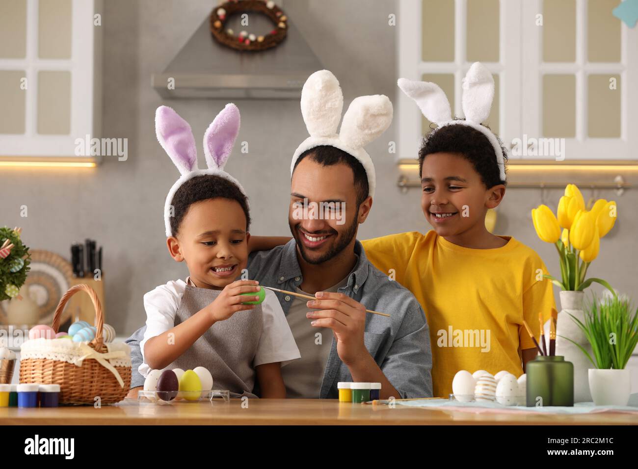 Happy African American father and his cute children painting Easter ...