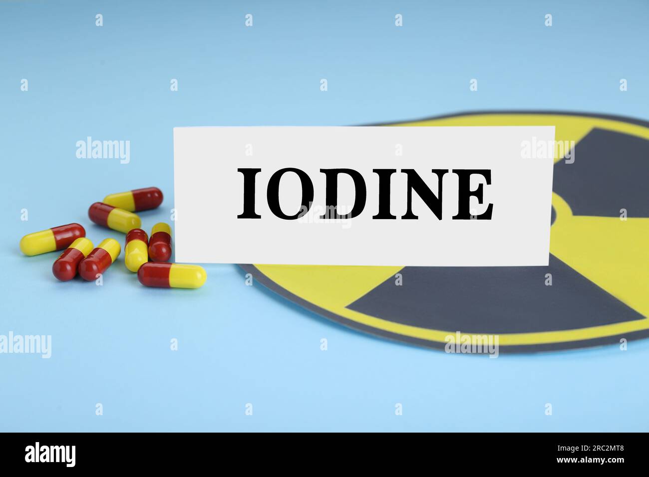 Paper note with word Iodine, radiation sign and pills on light blue ...