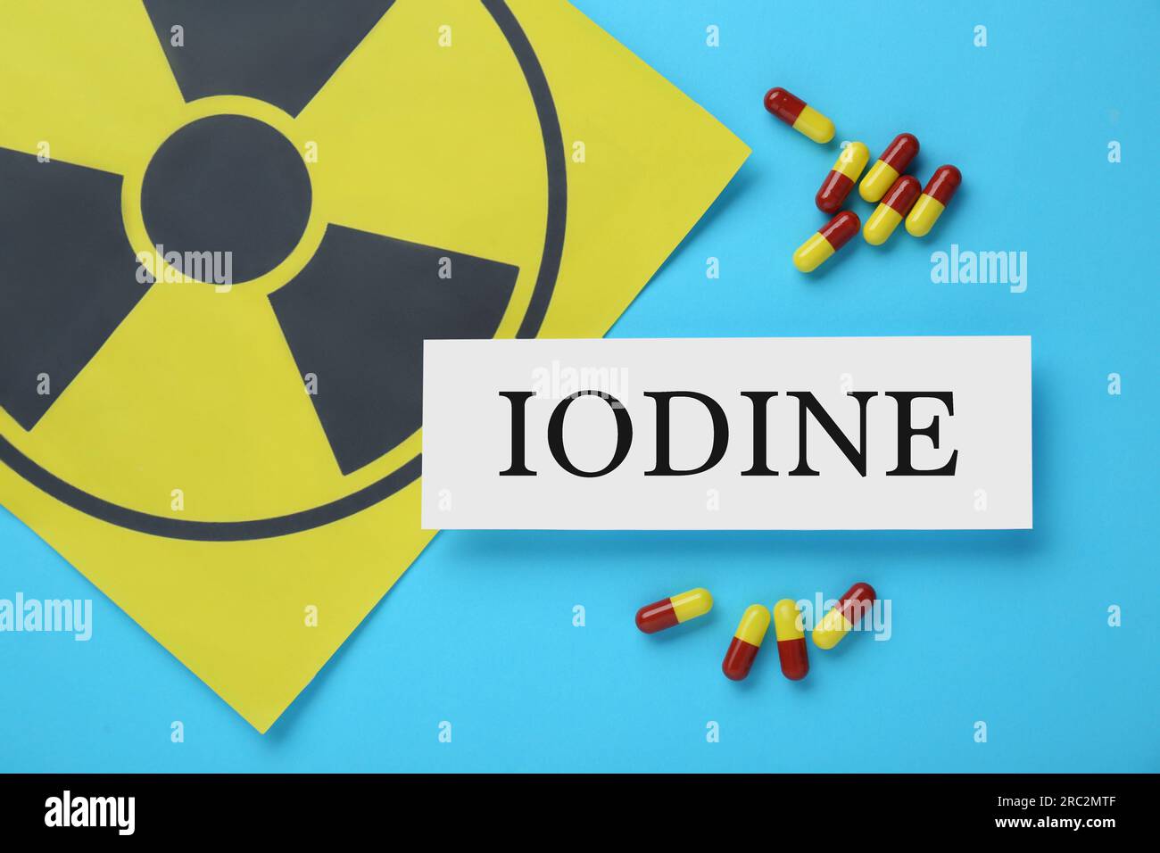 Paper note with word Iodine, radiation sign and pills on light blue ...