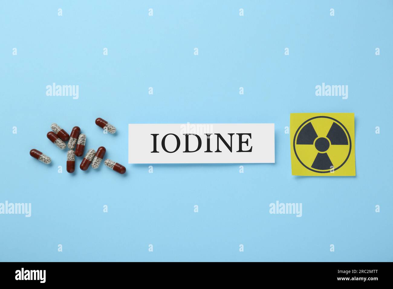 Paper note with word Iodine, radiation sign and pills on light blue ...