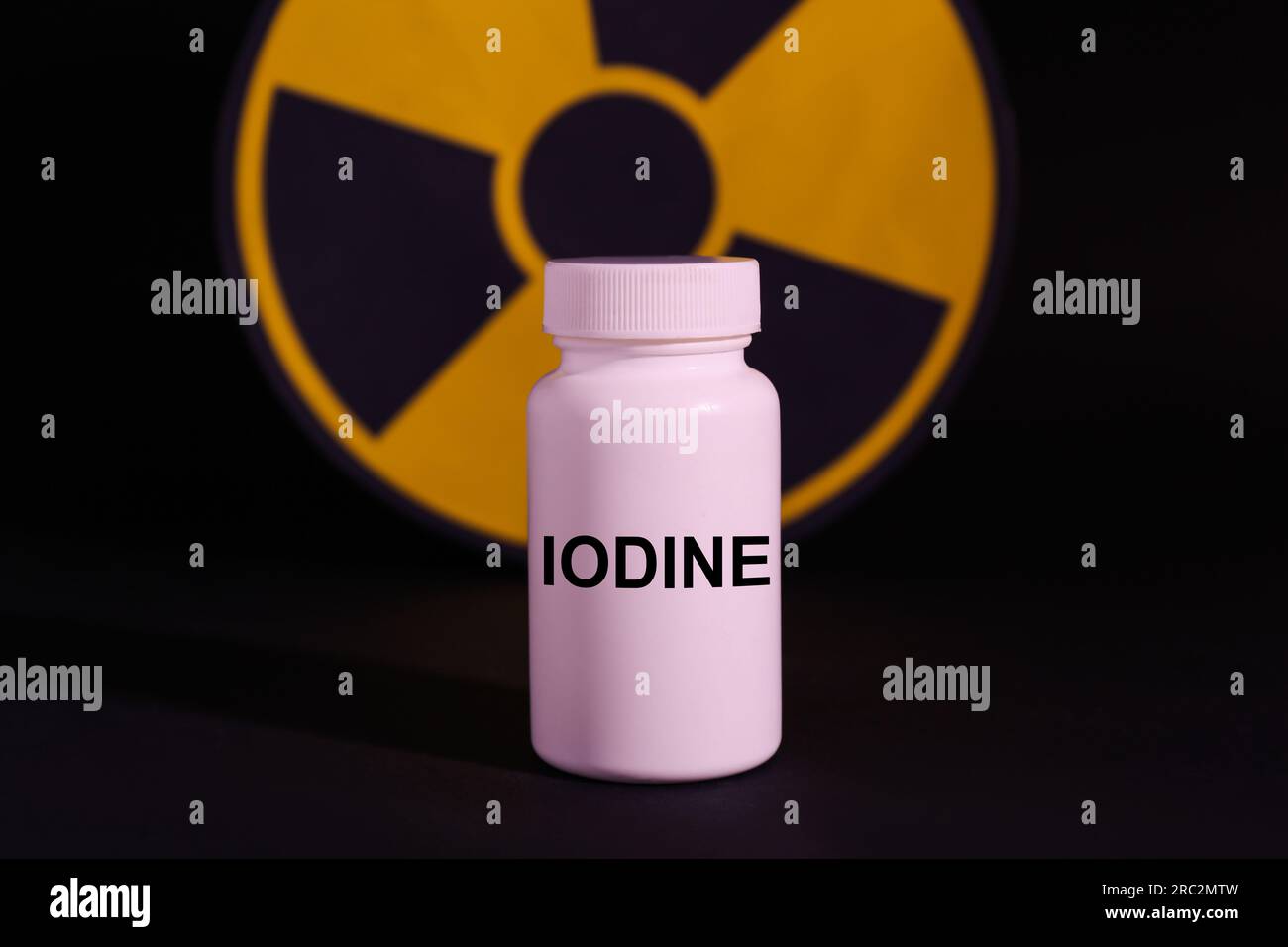 Plastic container of medical iodine and radiation sign on black ...