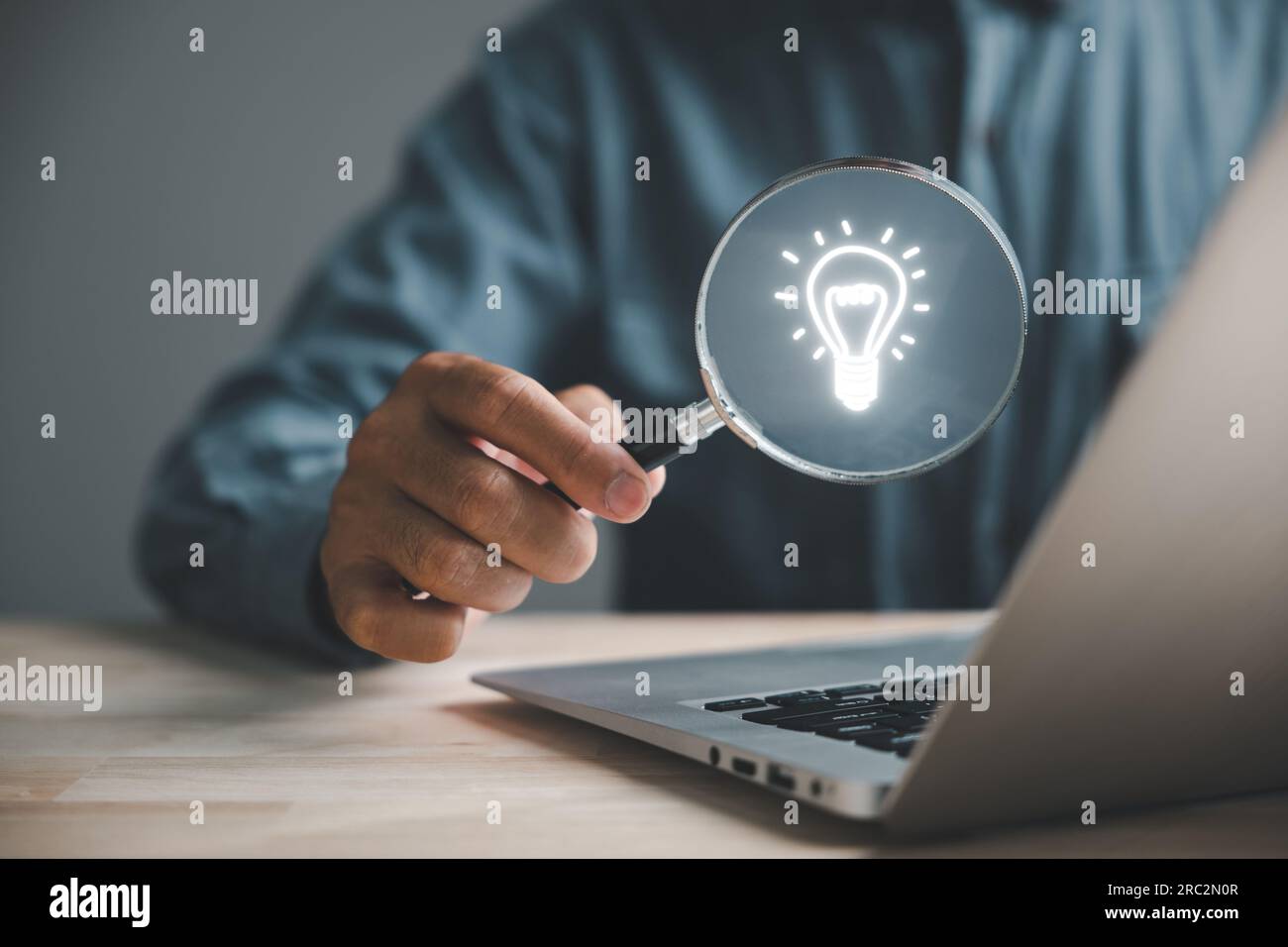 Magnifying glass in businessman's hand reveals light bulb Stock Photo ...