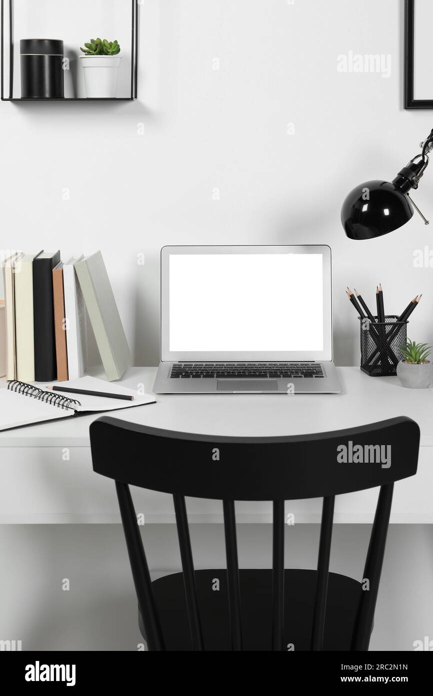 Cozy workspace with computer, lamp and stationery on wooden desk at ...