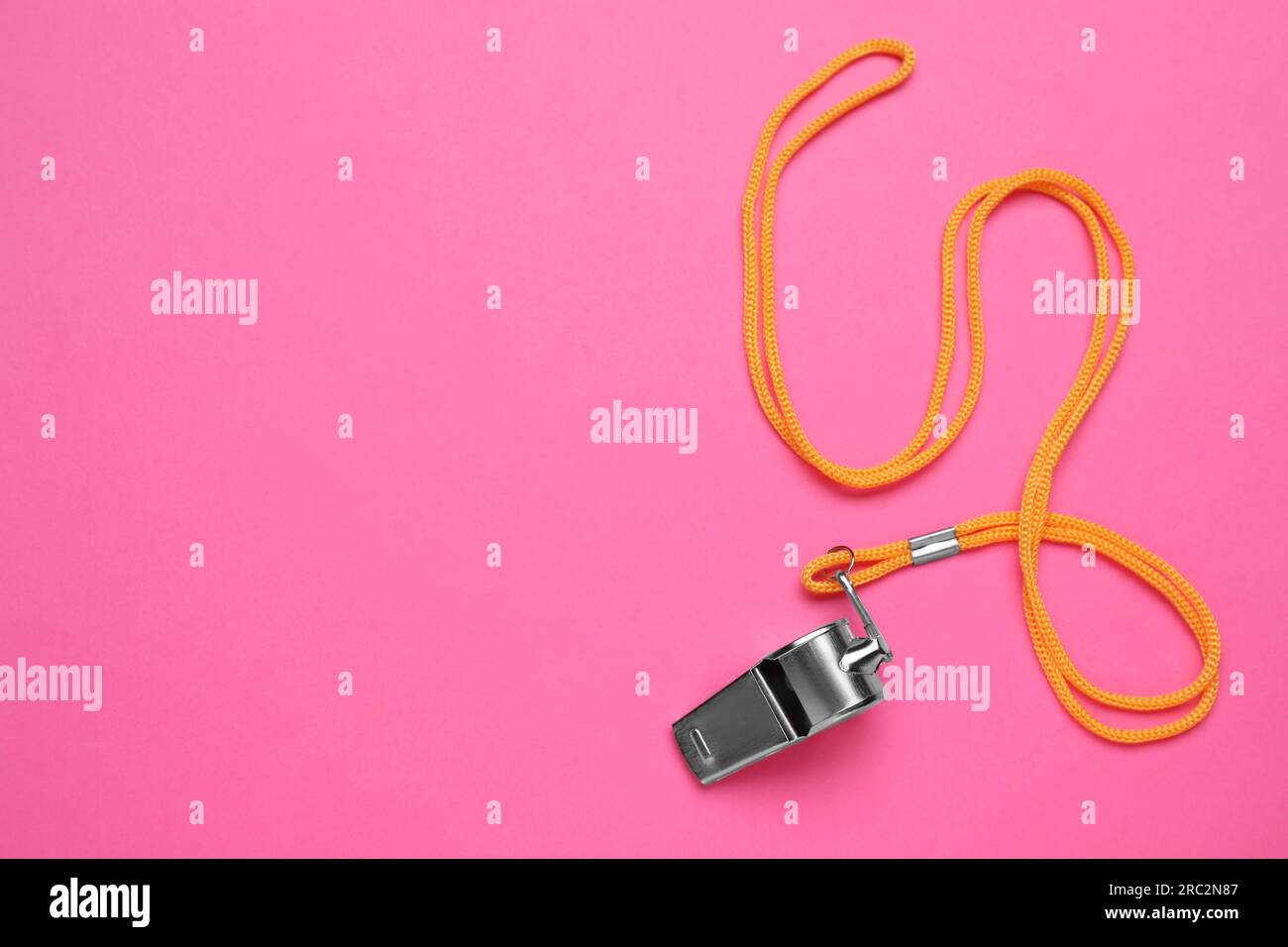 One metal whistle with cord on pink background, top view. Space for ...