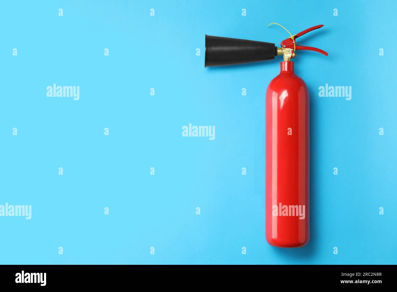 Fire extinguisher on light blue background, top view. Space for text ...