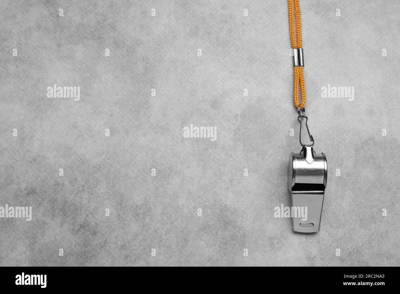 One metal whistle with cord on light grey table, top view. Space for ...