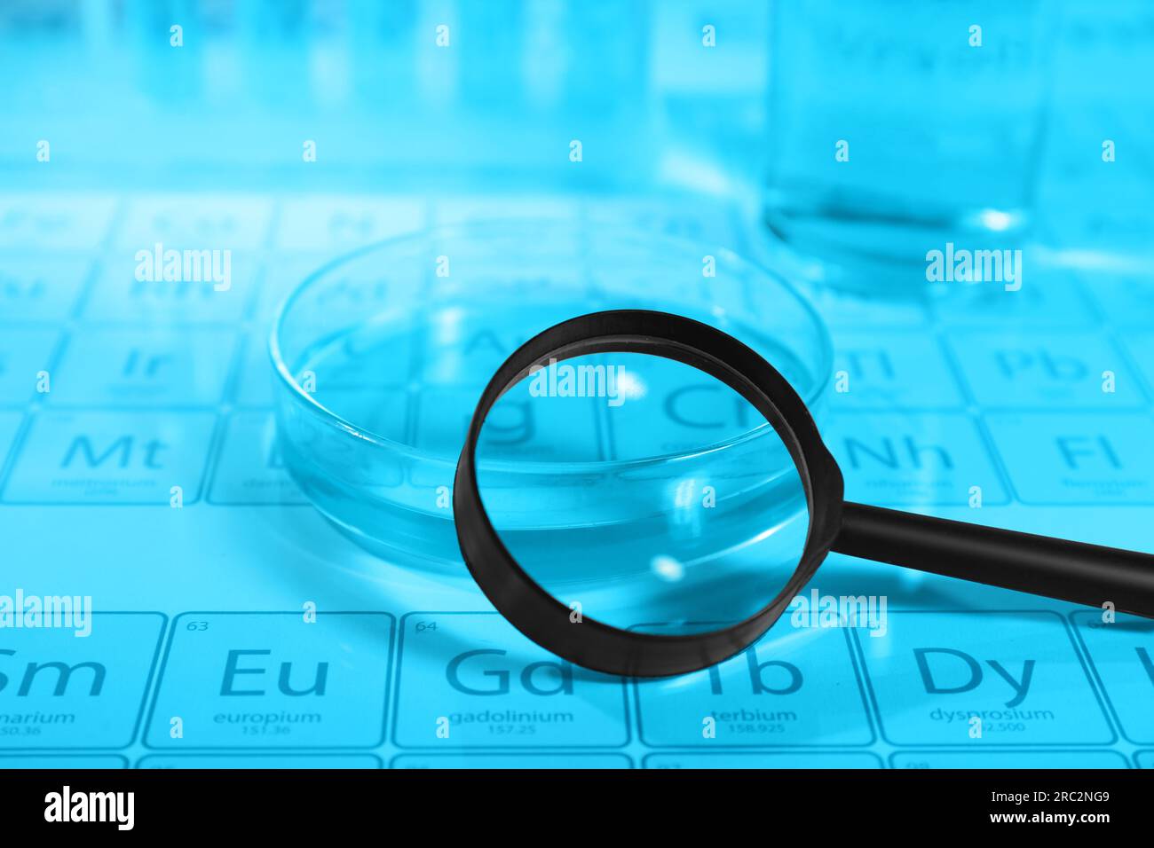 Petri dish, magnifying glass on periodic table of elements, closeup ...