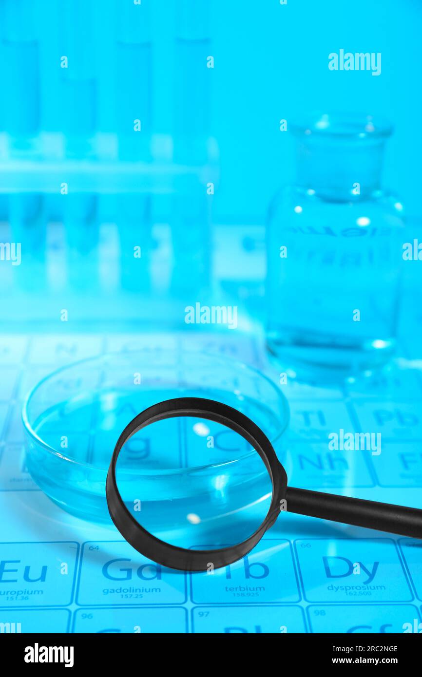 Petri dish, magnifying glass on periodic table of elements, closeup ...