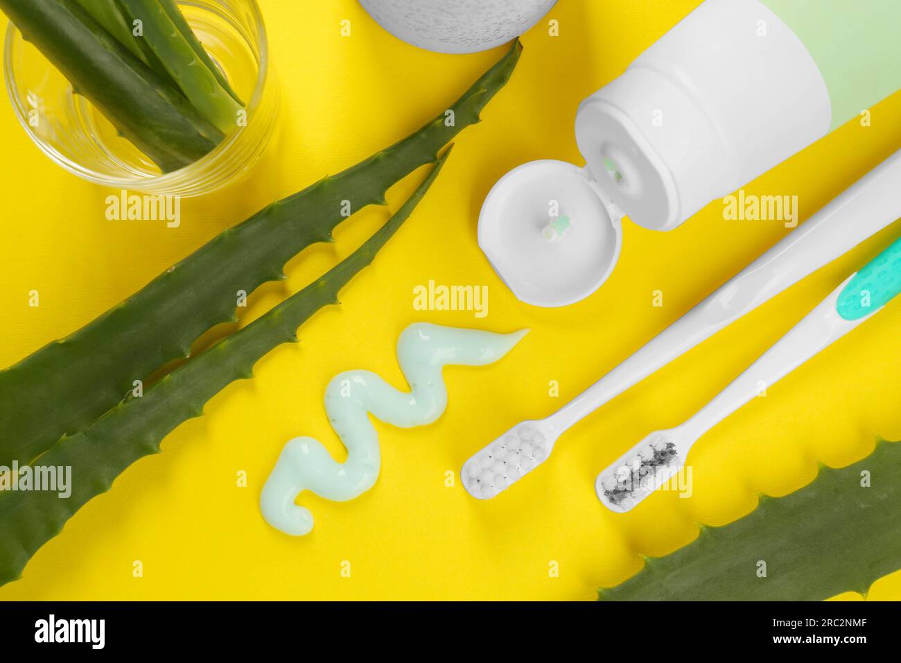 Aloe vera toothpaste, brushes and green leaves on yellow background ...