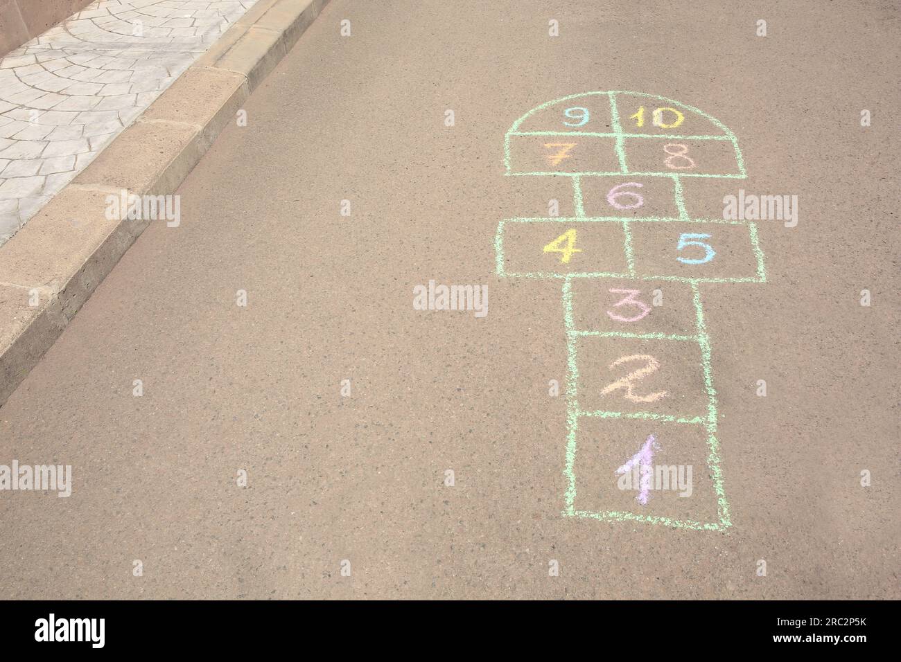 Hopscotch drawn with colorful chalk on asphalt outdoors. Space for text ...