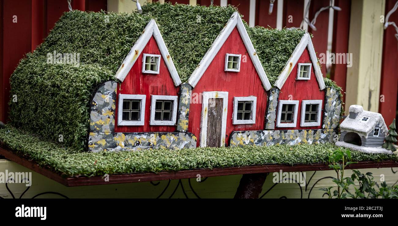 Three small red wooden elf houses with green moss roof, typical for ...