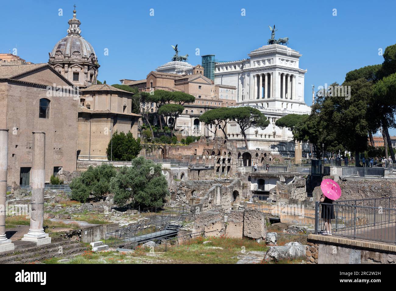 A lone tourist pictured with a parasol to protect herself from the heat ...