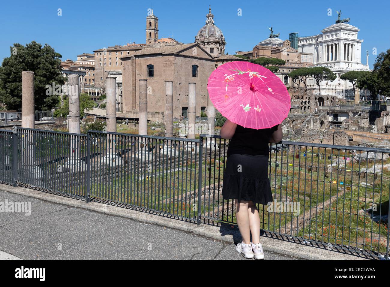 A lone tourist pictured with a parasol to protect herself from the heat ...