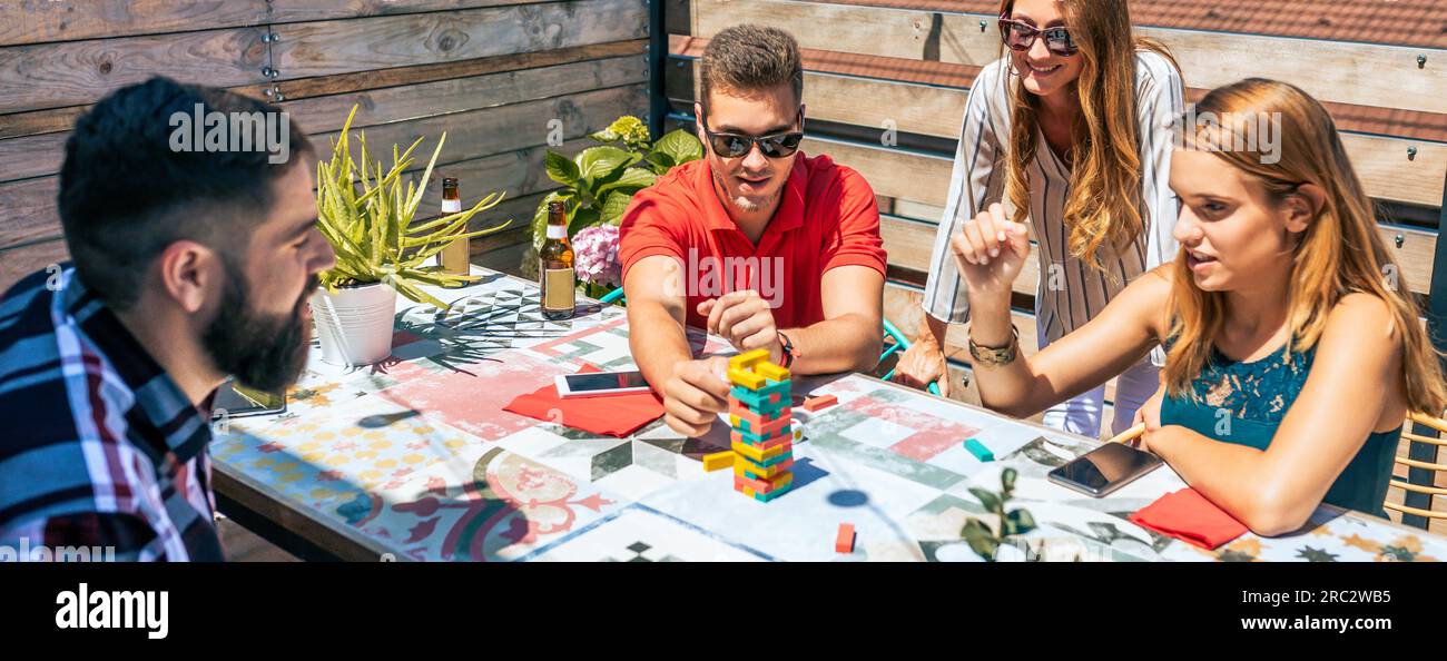 Group of friends playing with jenga game in rooftop on a summer party ...
