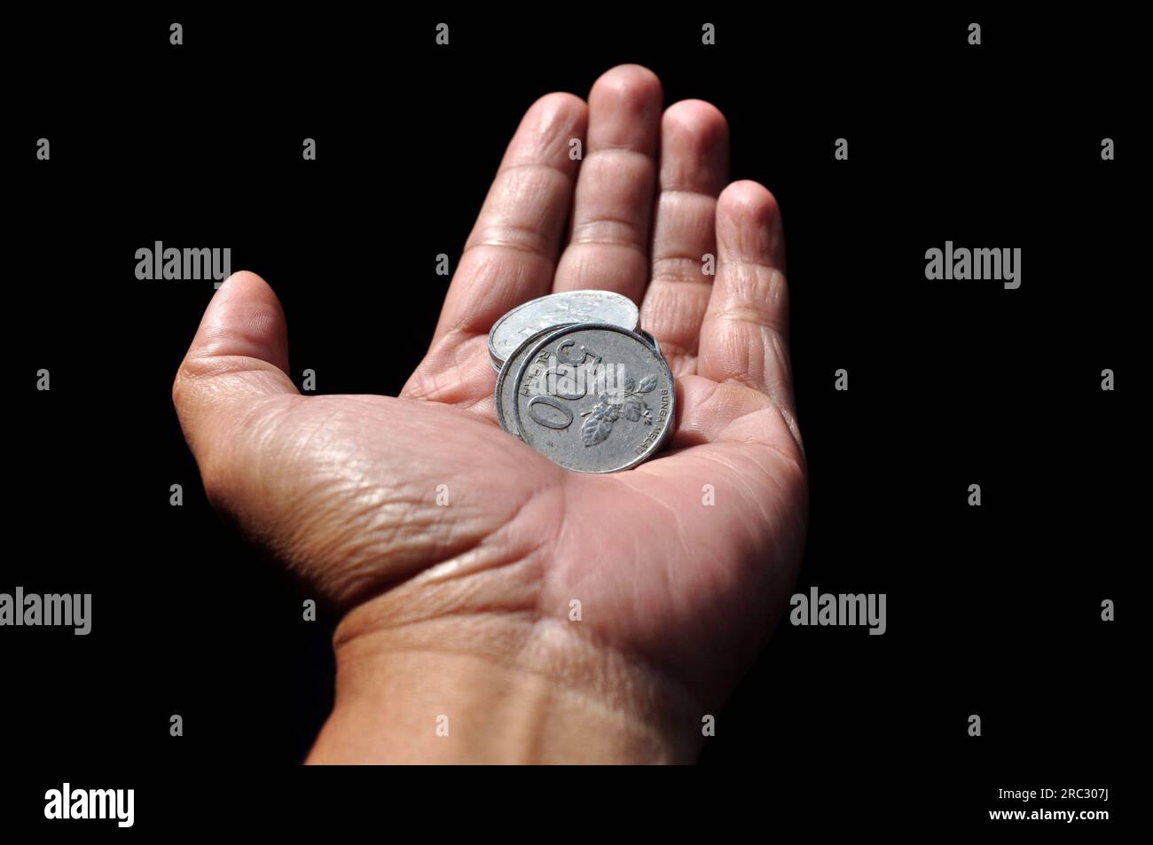 Coins on the palm of the hand on a black background Stock Photo - Alamy