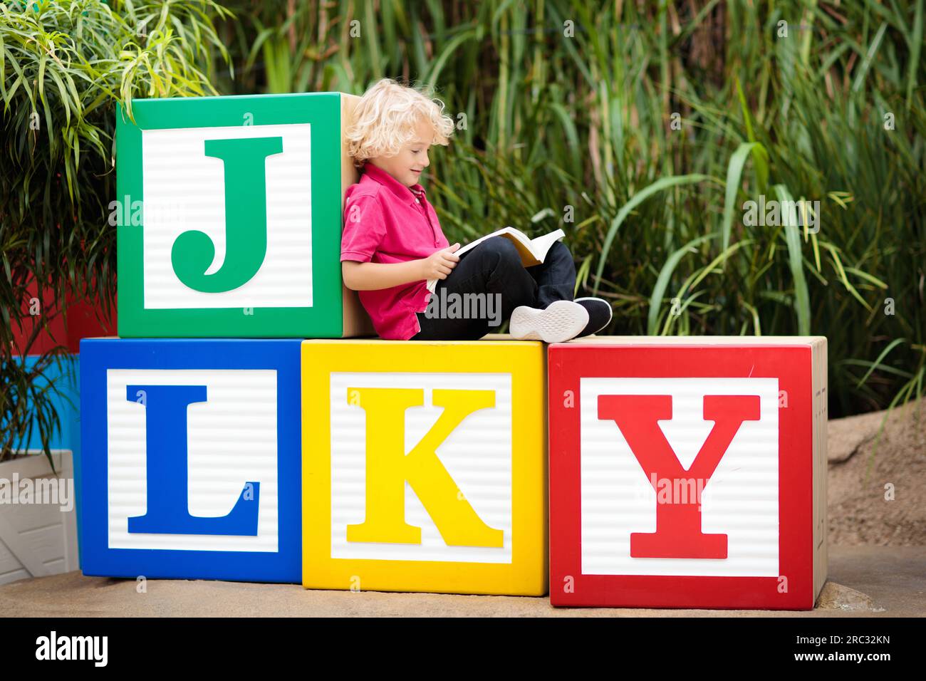 Child reading book in school yard. Kid learning abc letters. Little boy ...