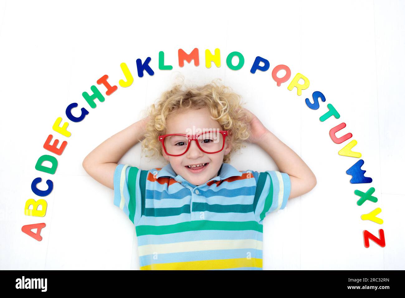 Happy preschool child learning to read and write playing with colorful ...