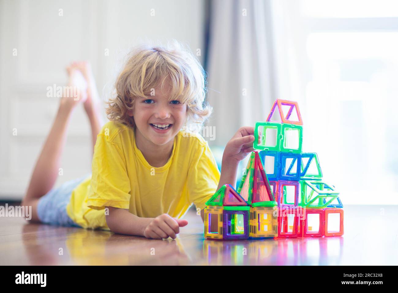 Child playing with magnetic building blocks. Little boy building tower ...