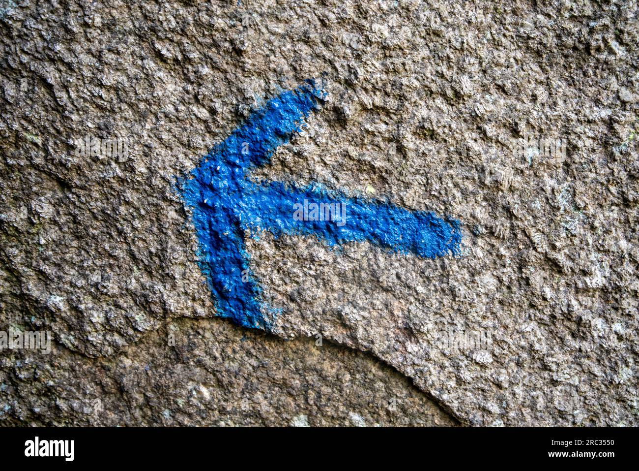 mountain pointer on blue arrow on a stone close-up, direction backward ...