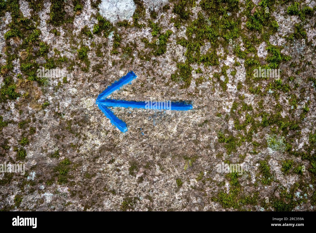 mountain pointer on blue arrow on a stone close-up, direction backward ...