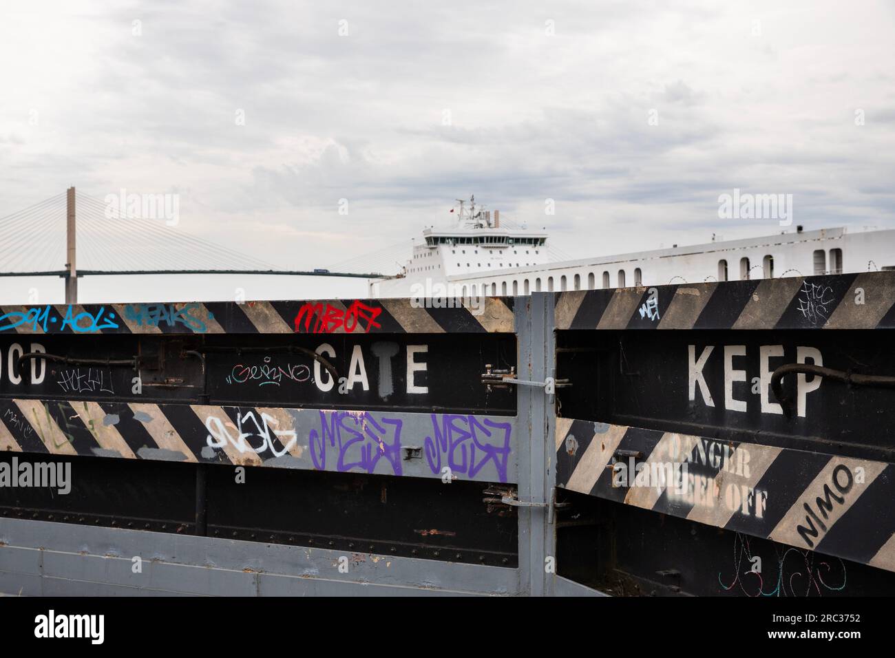 Flood defence gate along the Thames estuary, Thurrock, Essex, with ship ...