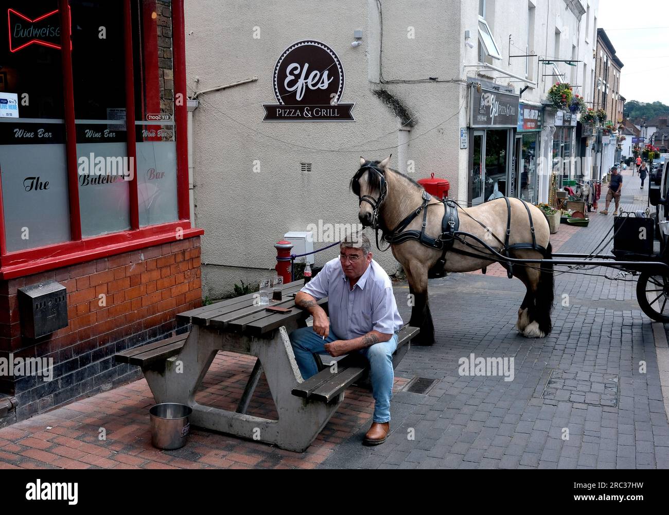 Man having a drink outside a pub bar with his horse and carriage tied ...