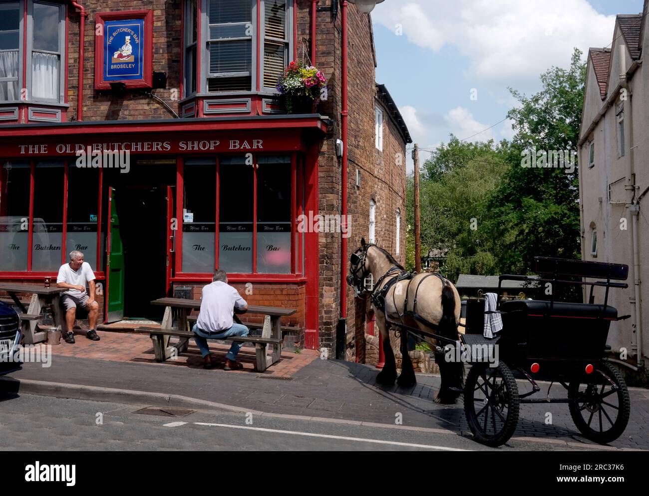Man having a drink outside a pub bar with his horse and carriage tied ...