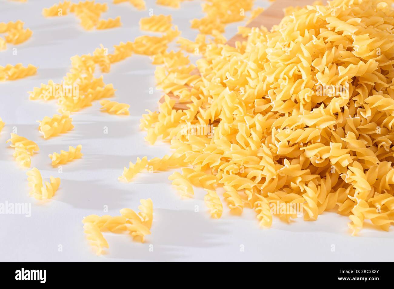 Uncooked Fusilli Pasta Scattered on Wooden Board and White Table. Raw ...
