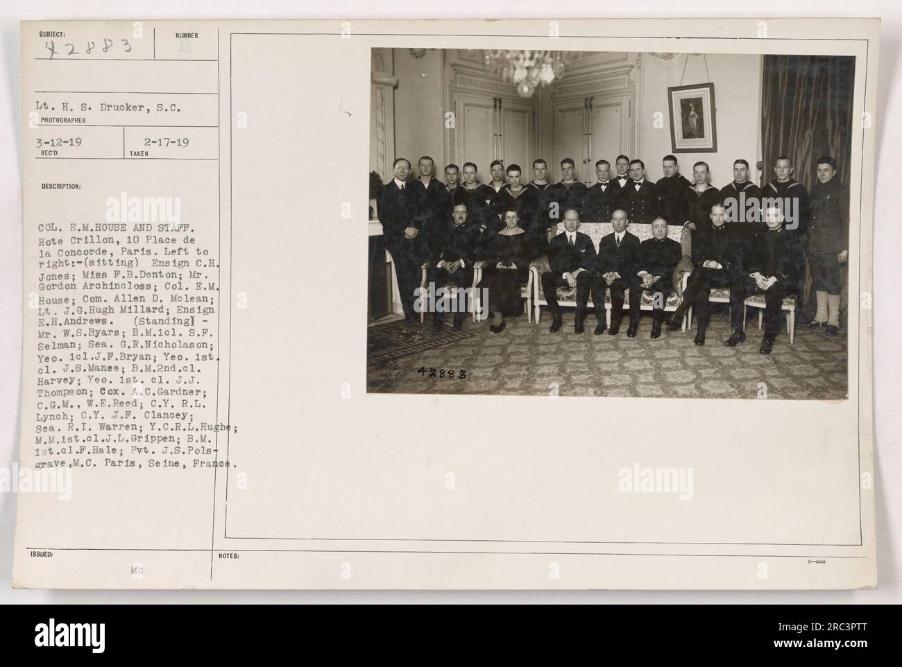 The image shows military personnel and civilian individuals sitting and ...