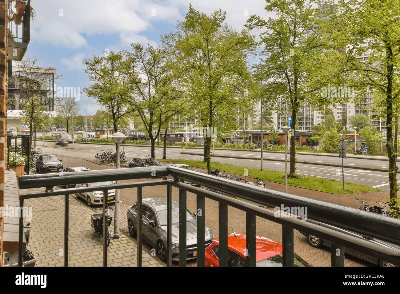 a balcony with cars parked on the side and trees lining the street in ...