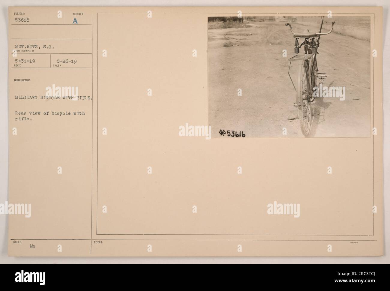 A rear view of a military bicycle equipped with a rifle. The photograph ...