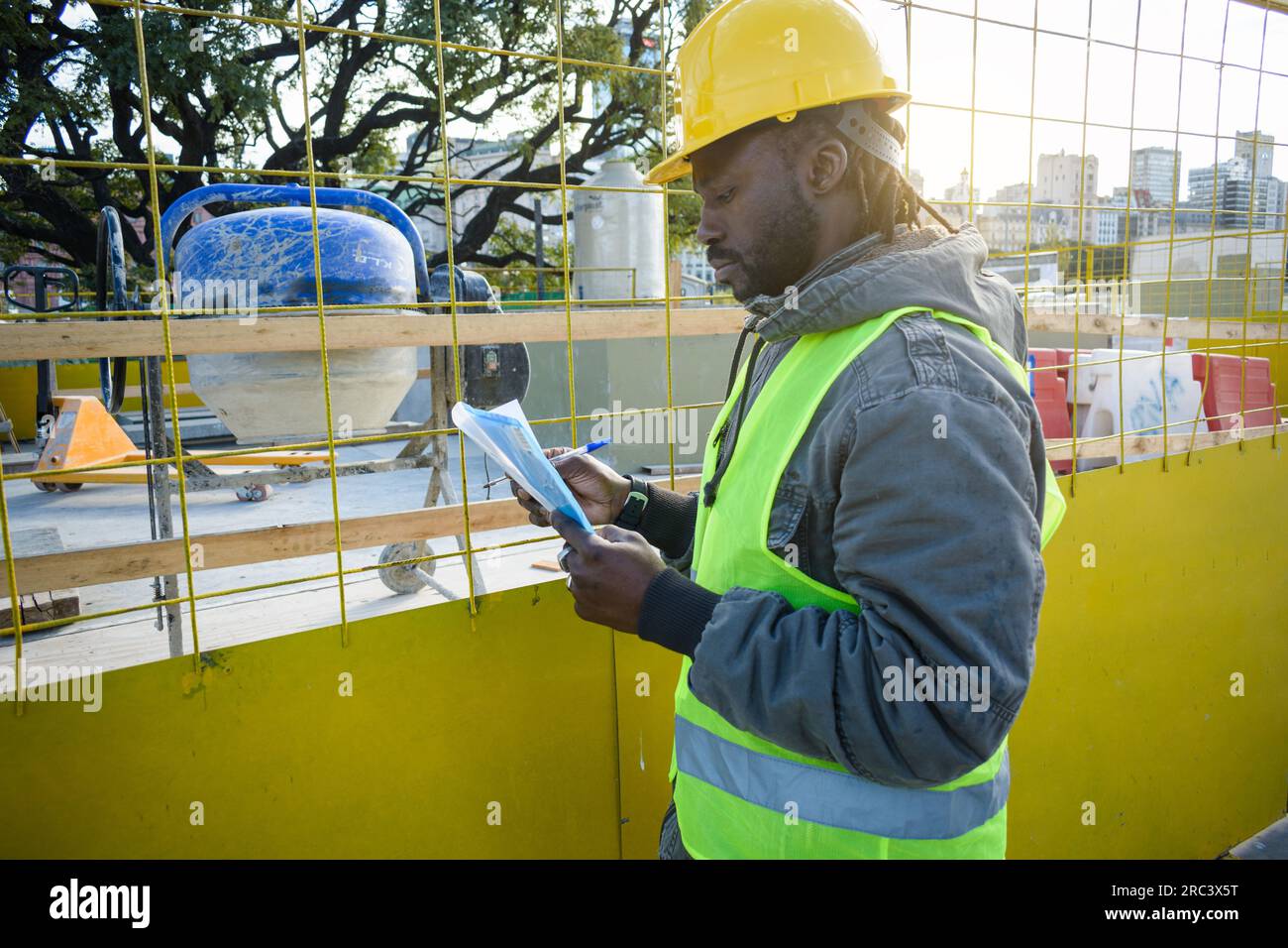 young civil engineer man with yellow safety helmet and long jacket ...