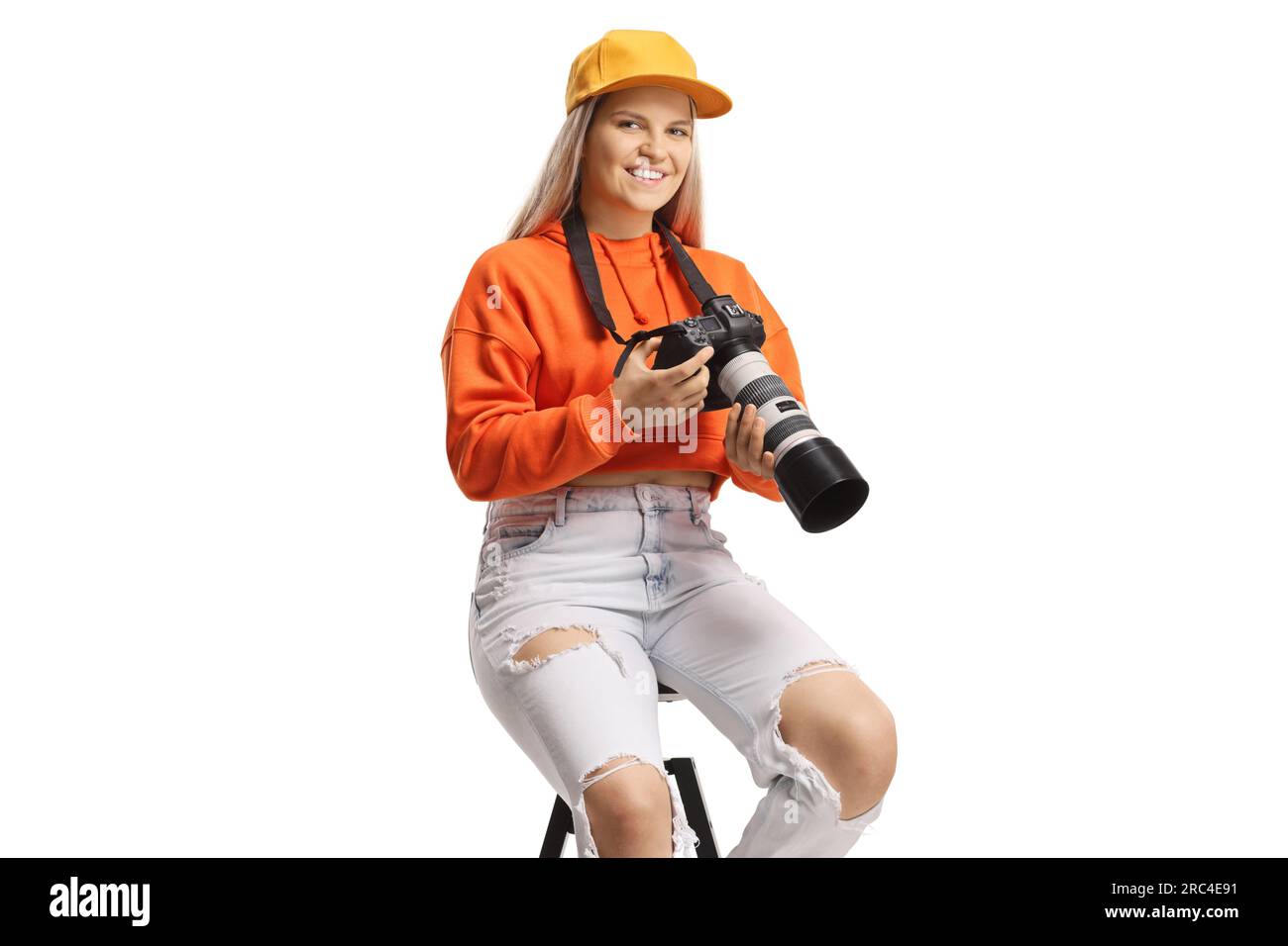 Female photographer sitting on a chair and holding a camera isolated on ...