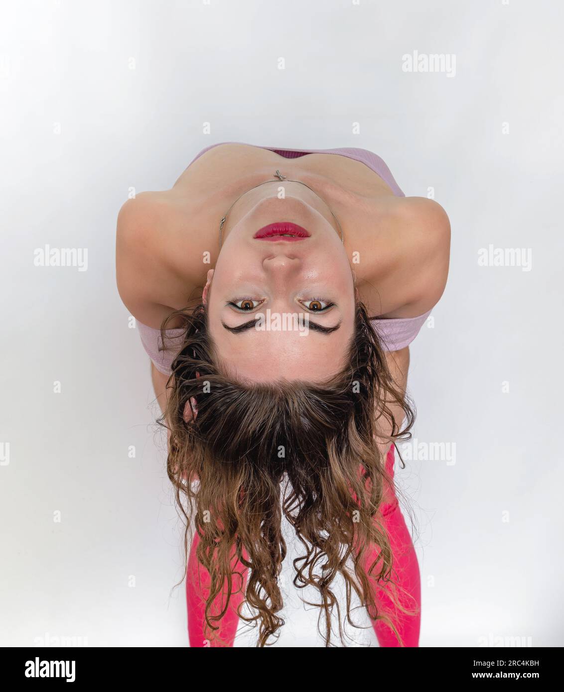Woman poses in studio, leaning back. Inverted face with bright makeup ...