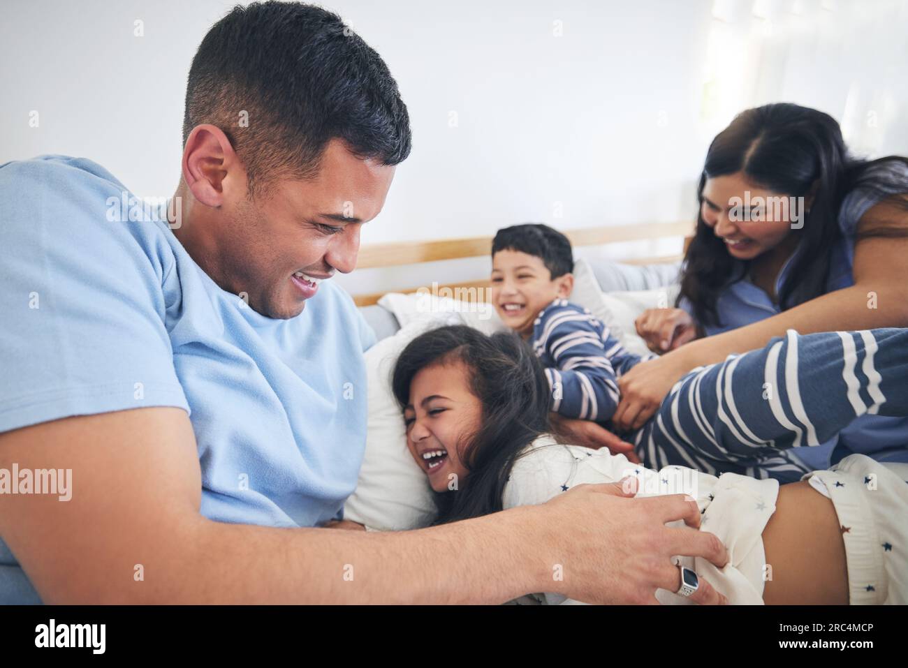Family, tickle and play on bed with fun and smile in a home with ...