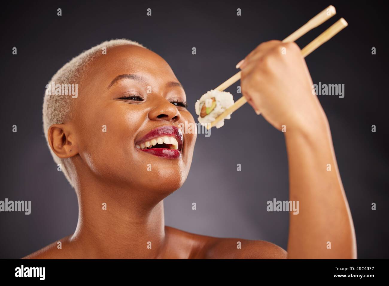 Face, eating and woman with sushi and chopsticks in studio for healthy ...