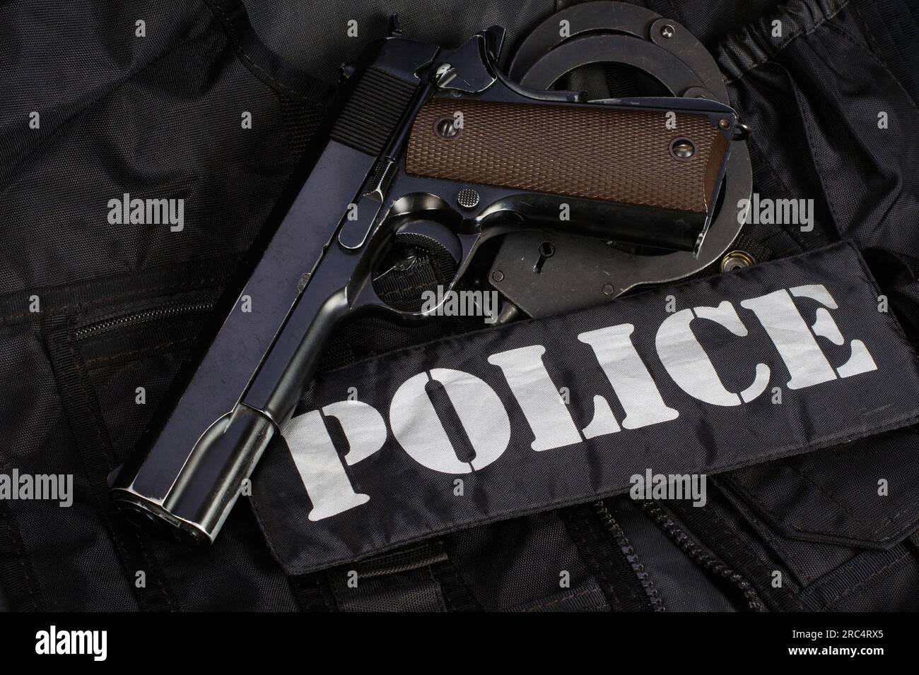Police handgun with handcuffs on black uniform background Stock Photo ...