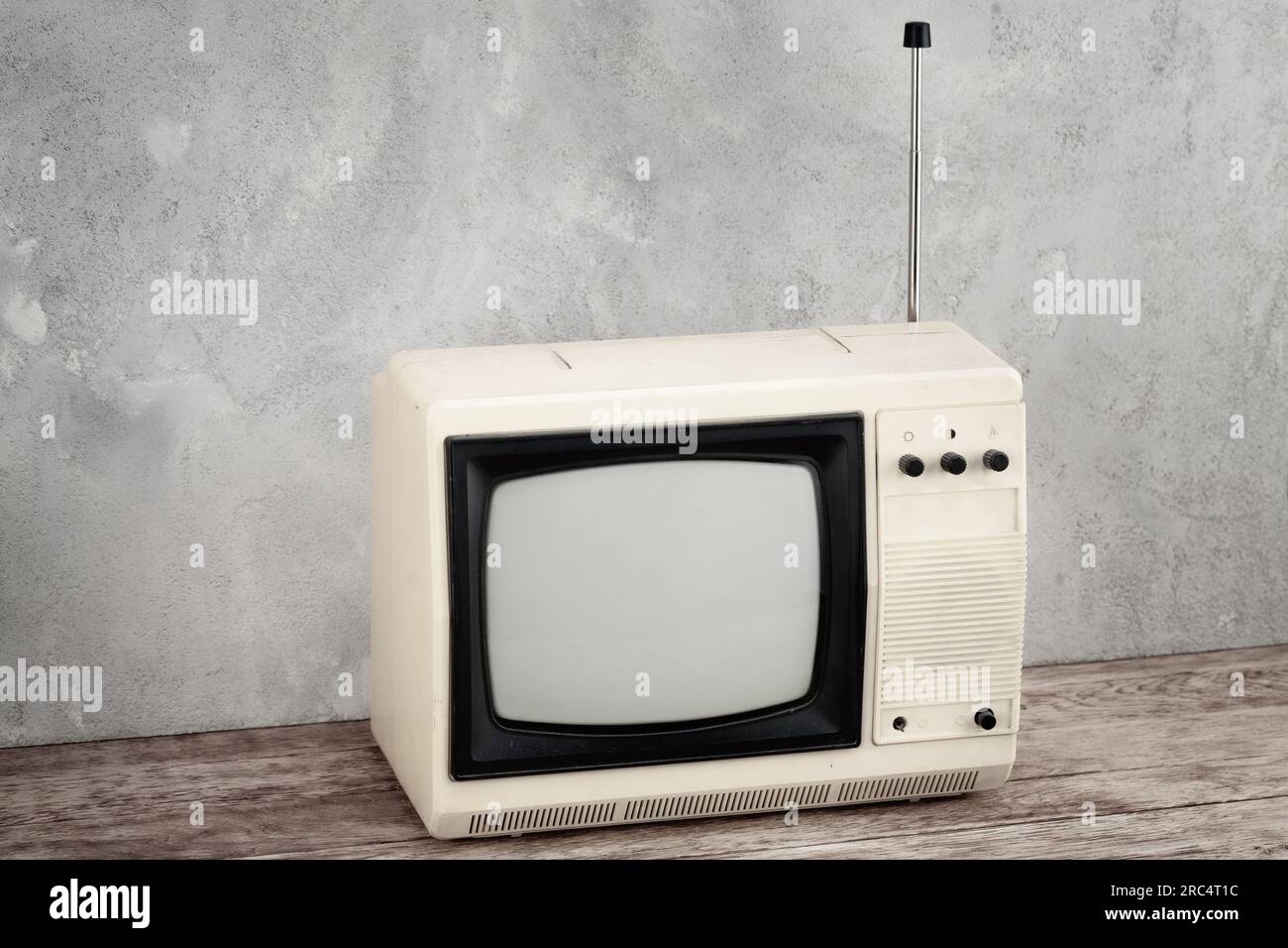 Vintage analog small TV set stand on wooden floor front grey concrete ...