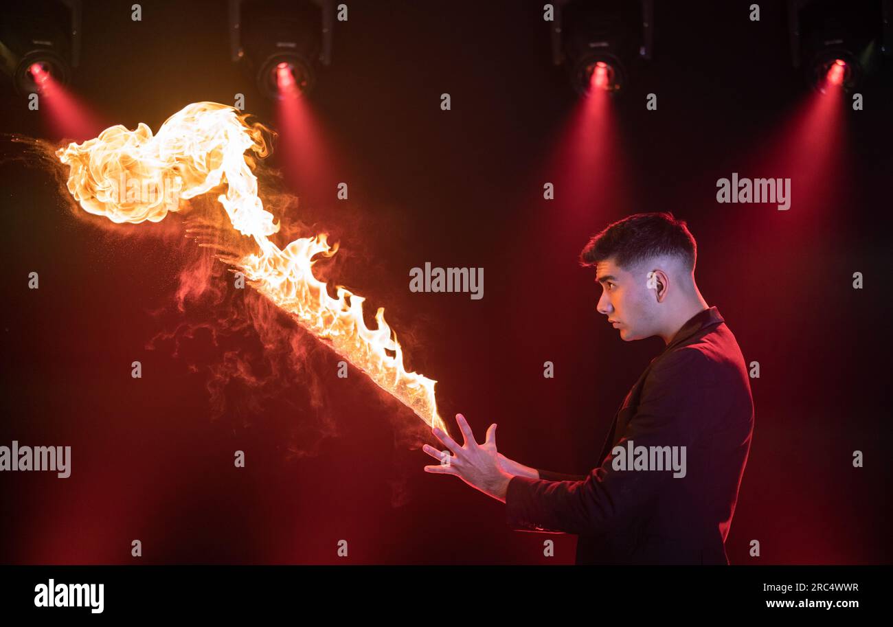 Side view of male prestidigitator in black suit showing magic trick ...