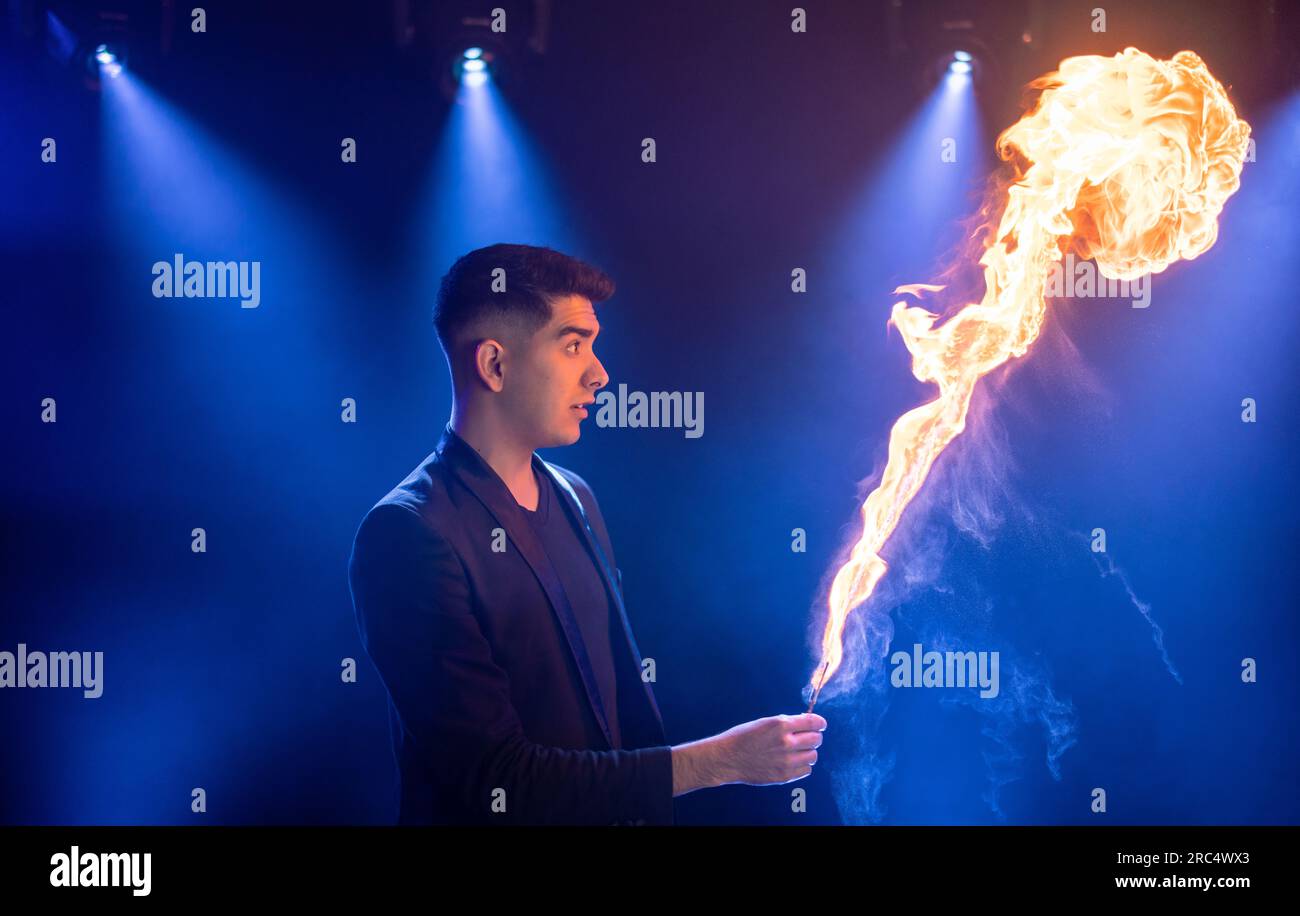 Side view of male prestidigitator in black suit showing magic trick ...