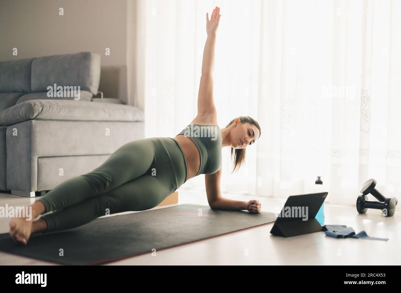 Side view of slim barefoot young female looking at screen of tablet and ...