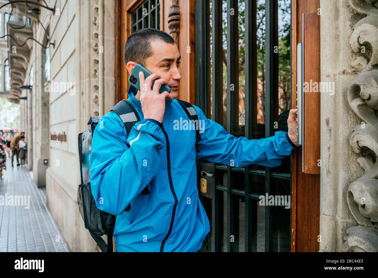 Delivery man with backpack calling on intercom and speaking on ...