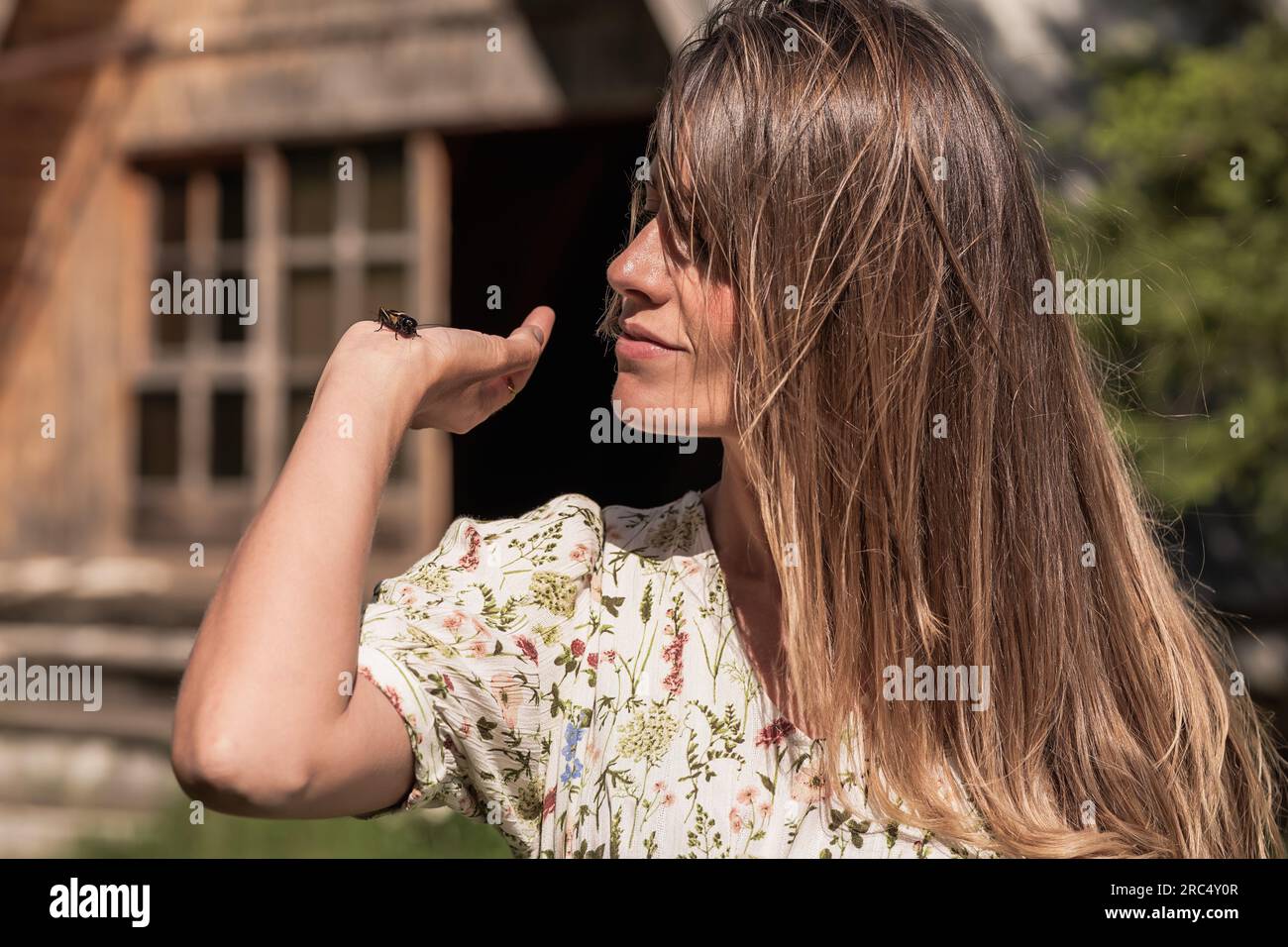Content female in summer dress holding cute bug on hand while spending ...