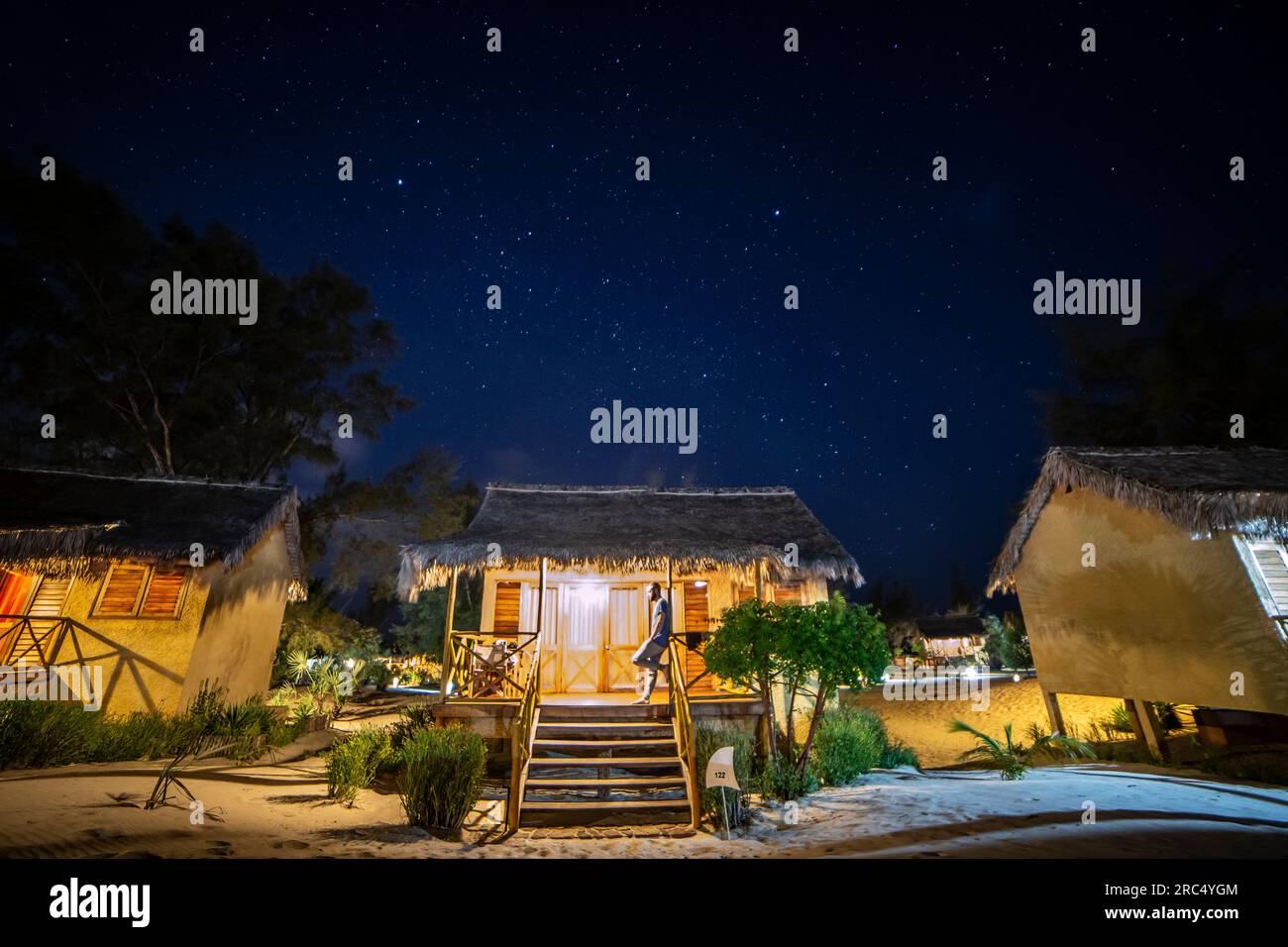 Anonymous male tourist standing near illuminated entrance of cottage in ...